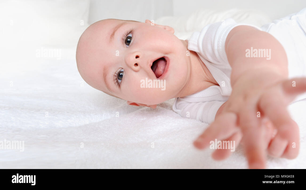 Happy laughing baby relax on bed. Beautiful happy small infant lying on ...