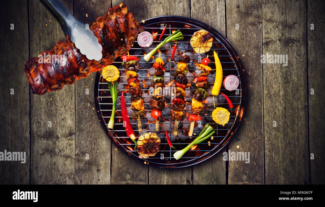 Top view of ribs and fresh meat and vegetable on grill placed on wooden ...