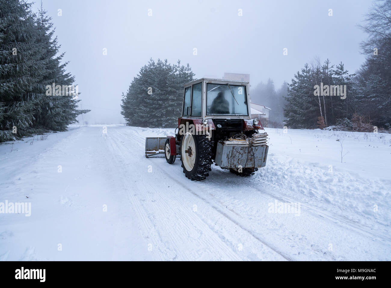 Red snowblower grader clears snow covered ski resort road in mountains ...