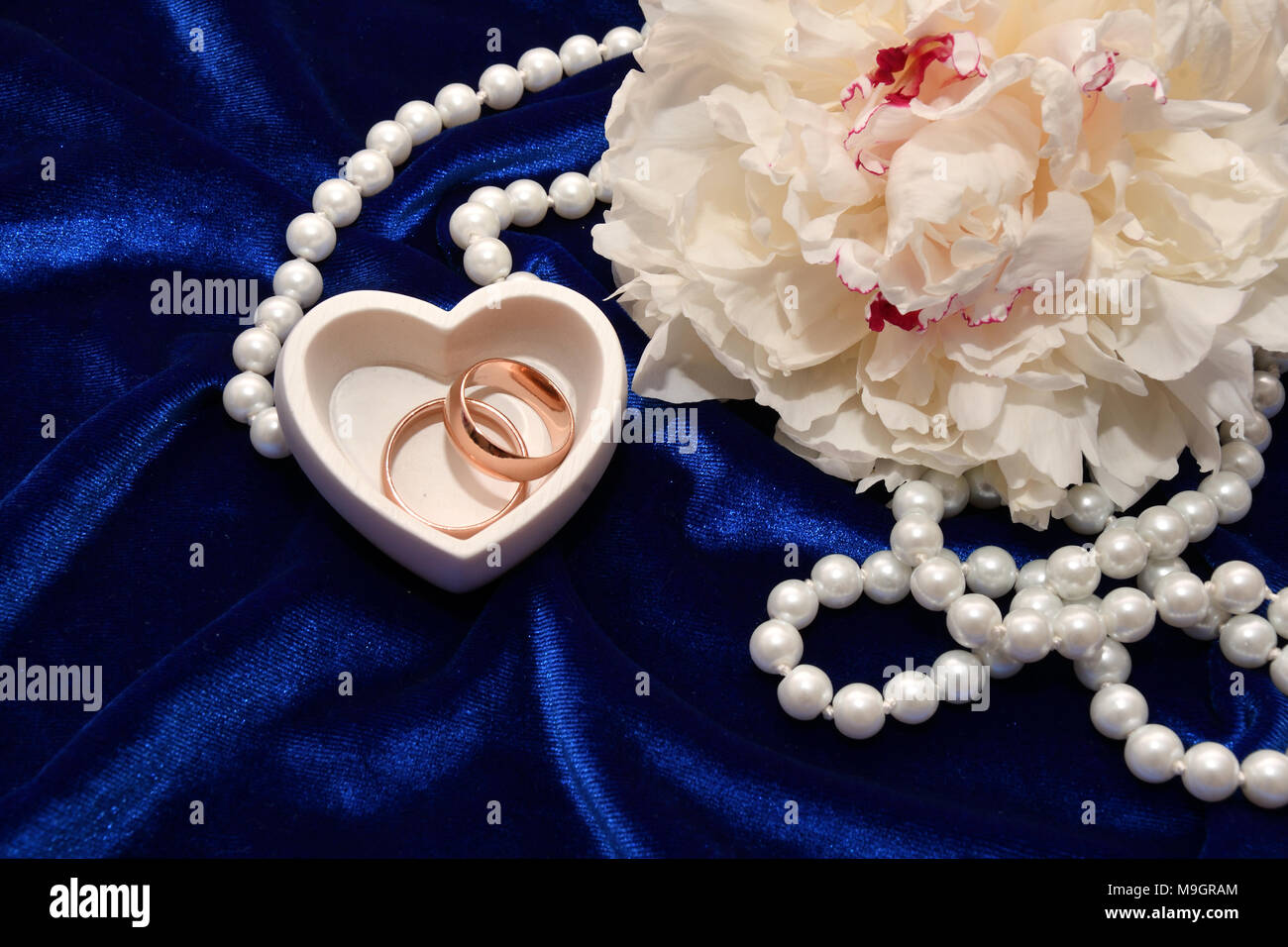 Two wedding rings for bride and groom and Peony flower Stock Photo - Alamy