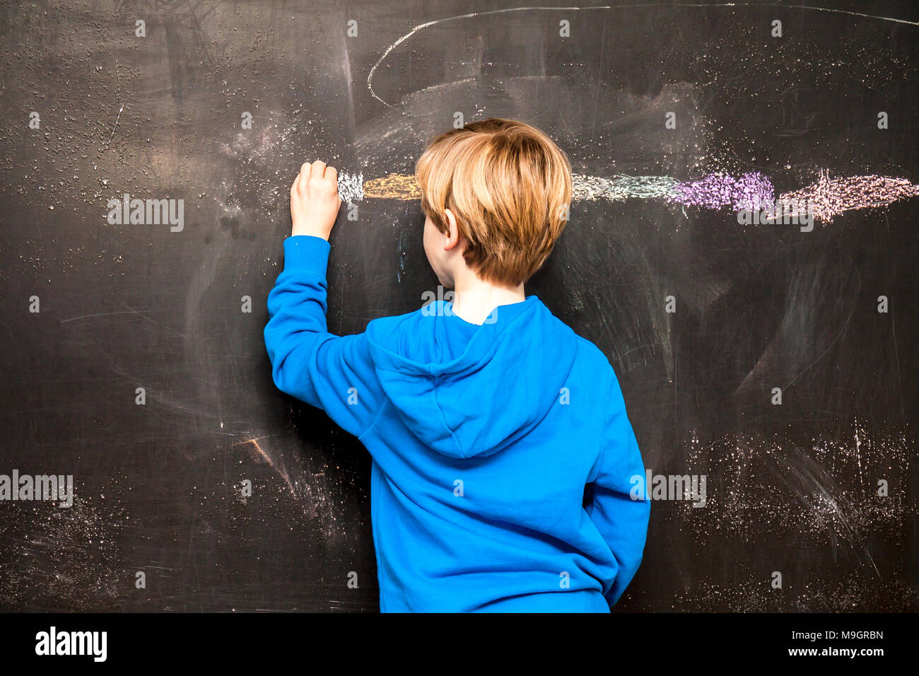 Back view of a little boy painting something on a chalkboard Stock ...