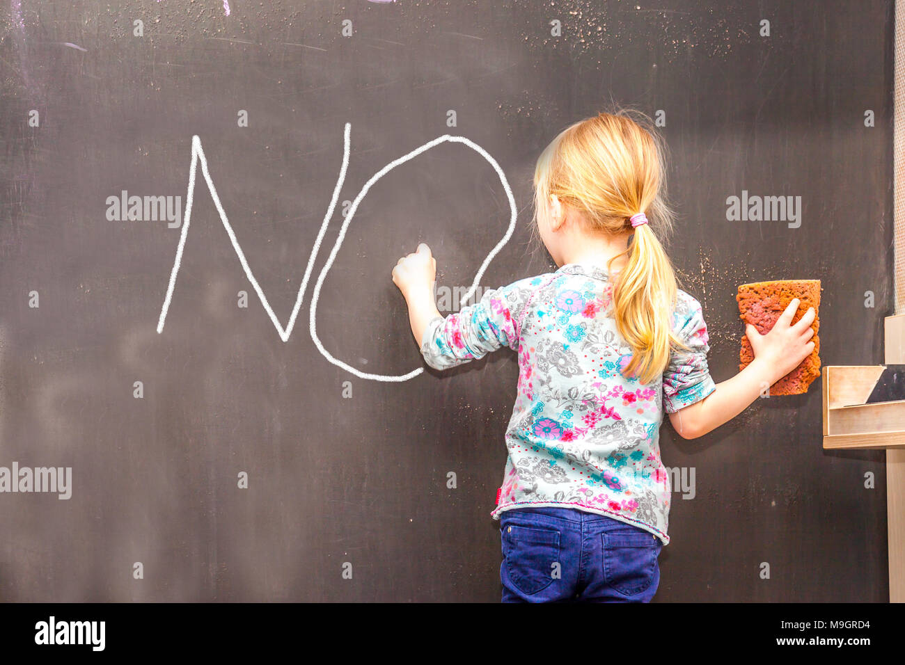 Cute little girl writing no on chalkboard in a classroom Stock Photo ...