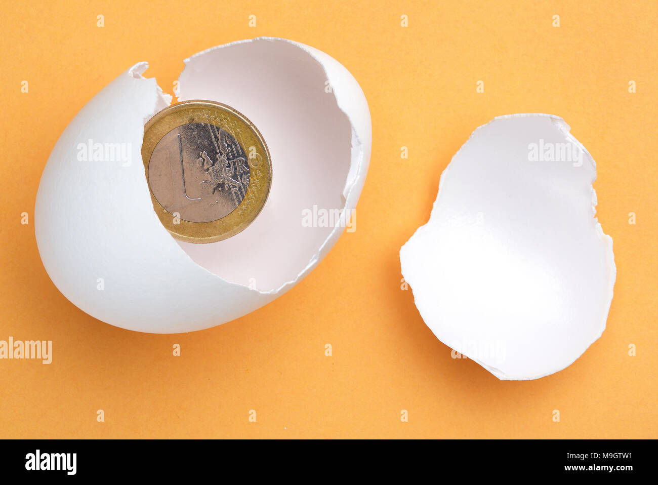 Euro coin in the eggshell on a yellow background Stock Photo - Alamy