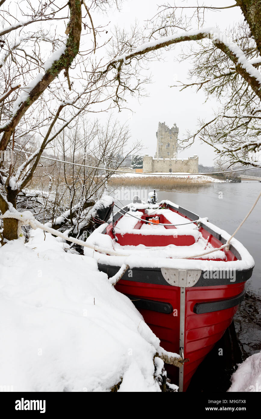Red fishing boat and Ross Castle in background as juxtaposition. Snowy ...