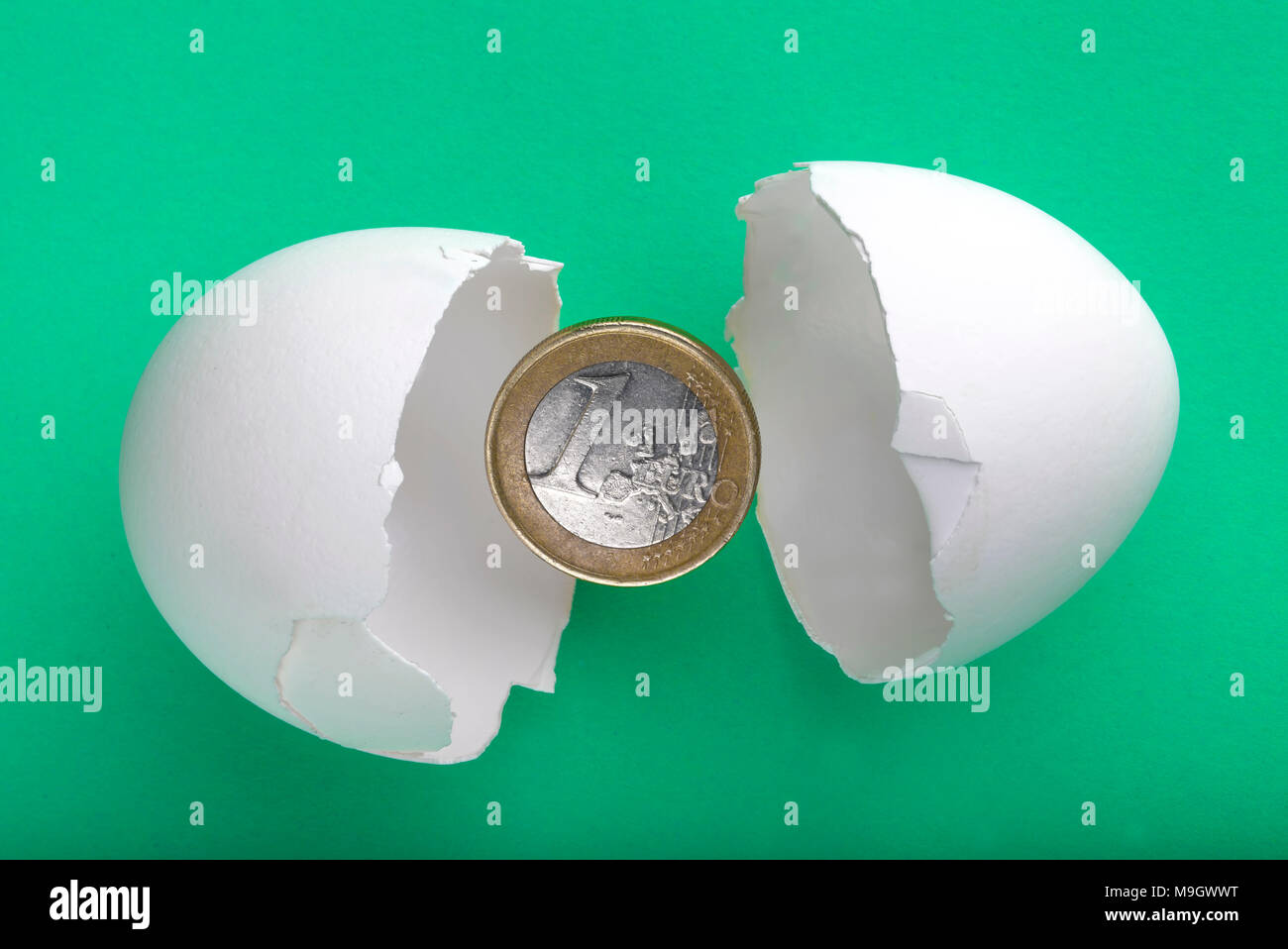 Euro coin in the eggshell on a green background Stock Photo - Alamy