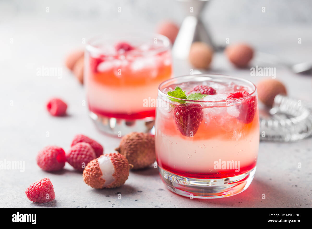 Refreshing cold lychee and raspberry cocktail in a glasses with ice and ...