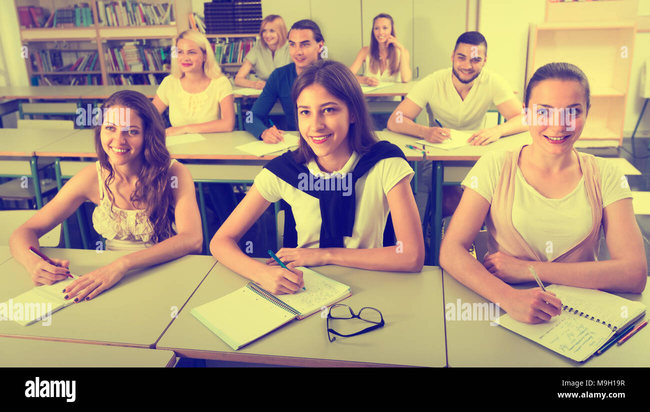 Happy college students in classroom writing a test Stock Photo - Alamy