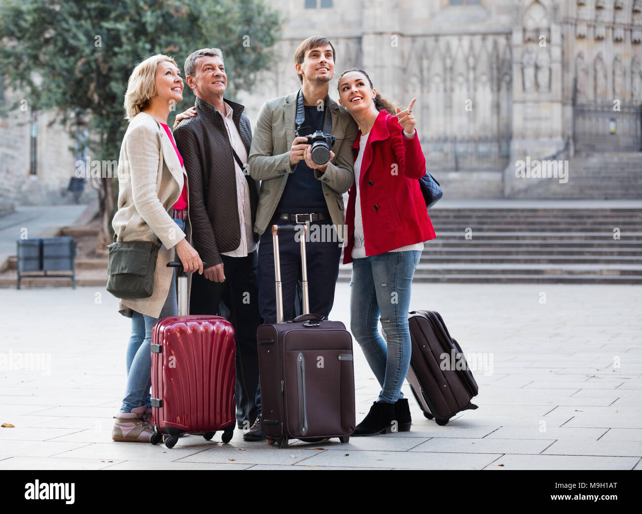 Two cheerful positive smiling couples with baggage sightseeing and ...