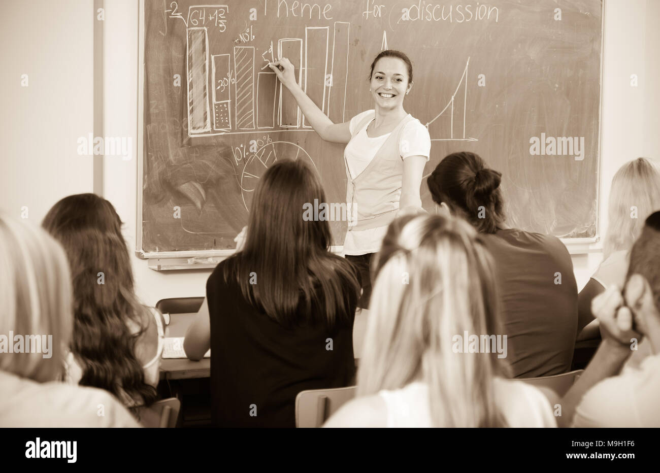 young girl standing at blackboard in classroom explains something Stock ...