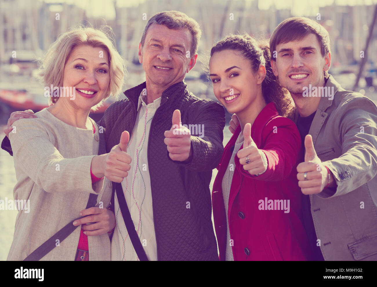 Close up of cheerful smiling tourists posing with thumbs up walking ...