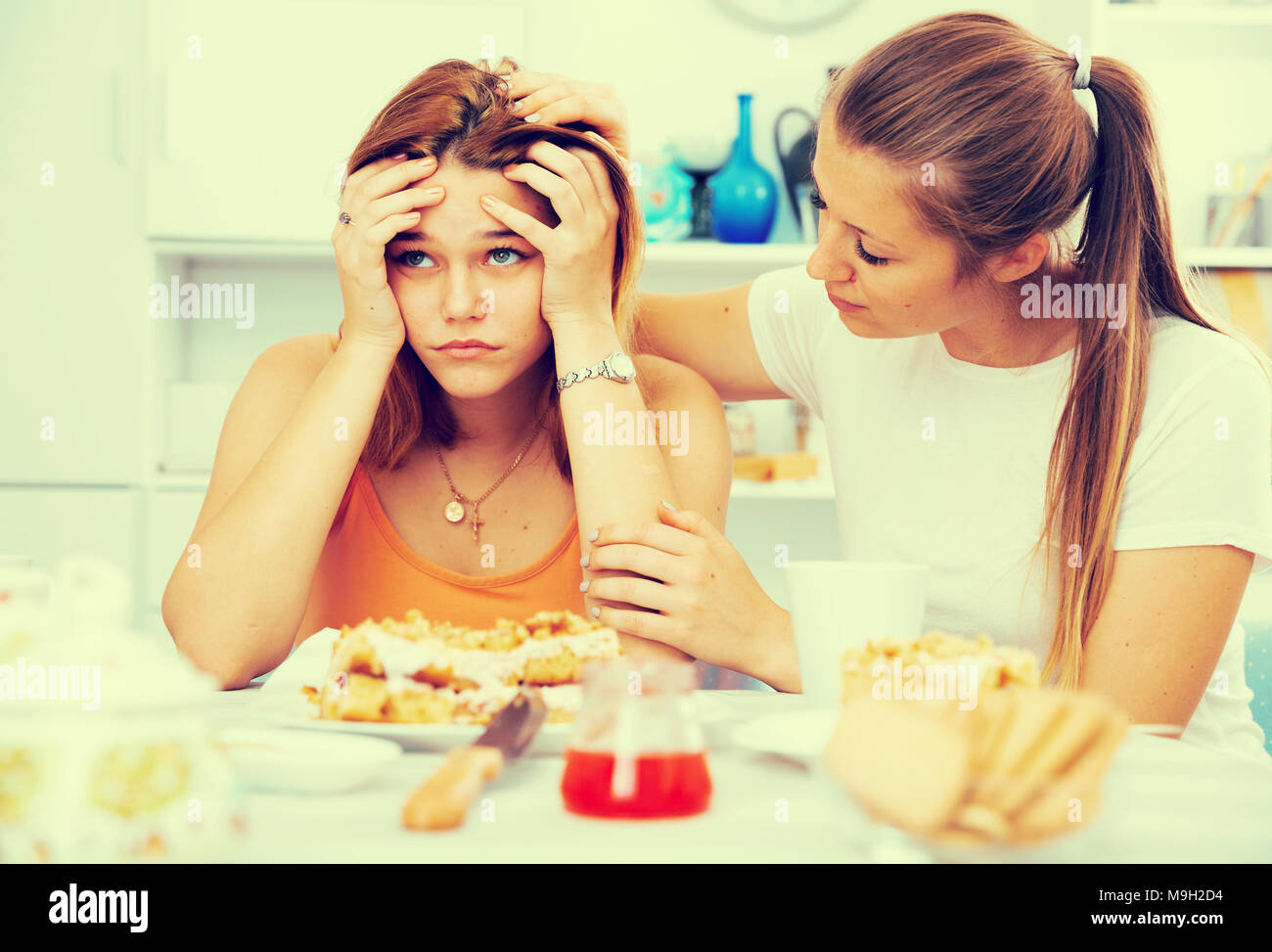 Portrait of female talking with sad girl friend at the kitchen Stock ...