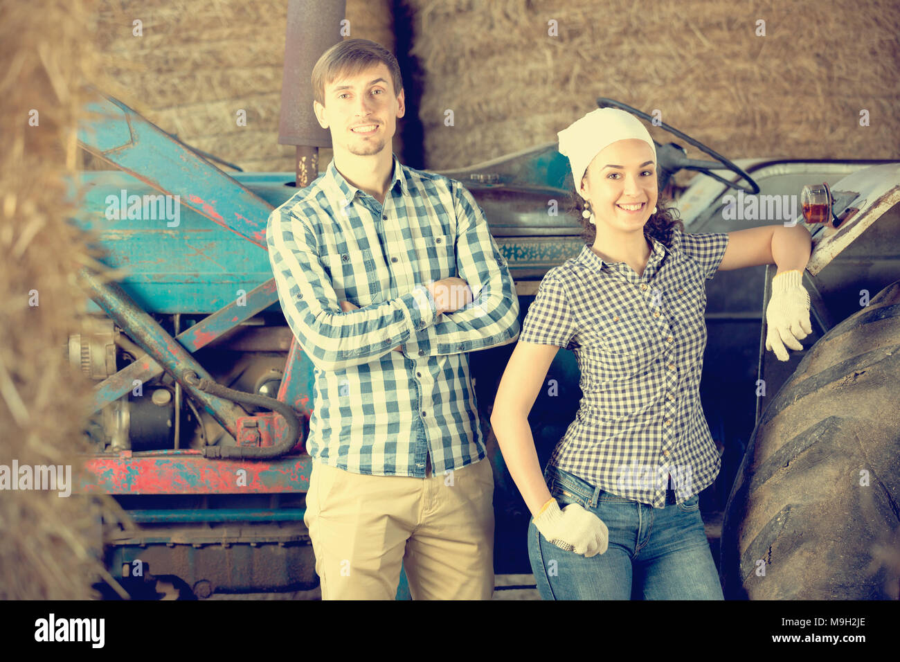 portrait of two young happy farmers taking a pause and holding a field ...