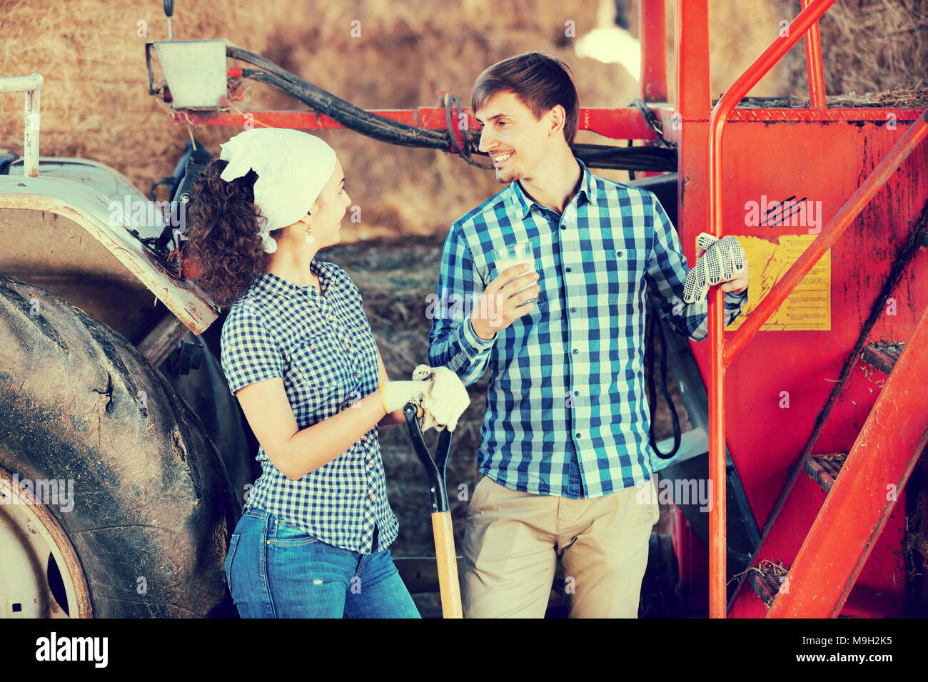 Portrait of two young happy farmers taking a pause and holding the ...
