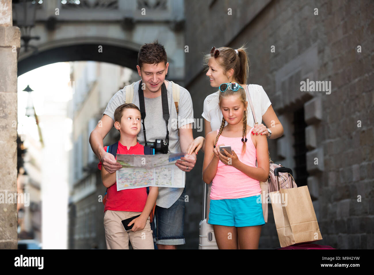 Family of tourists looking for destination using city map and phone ...
