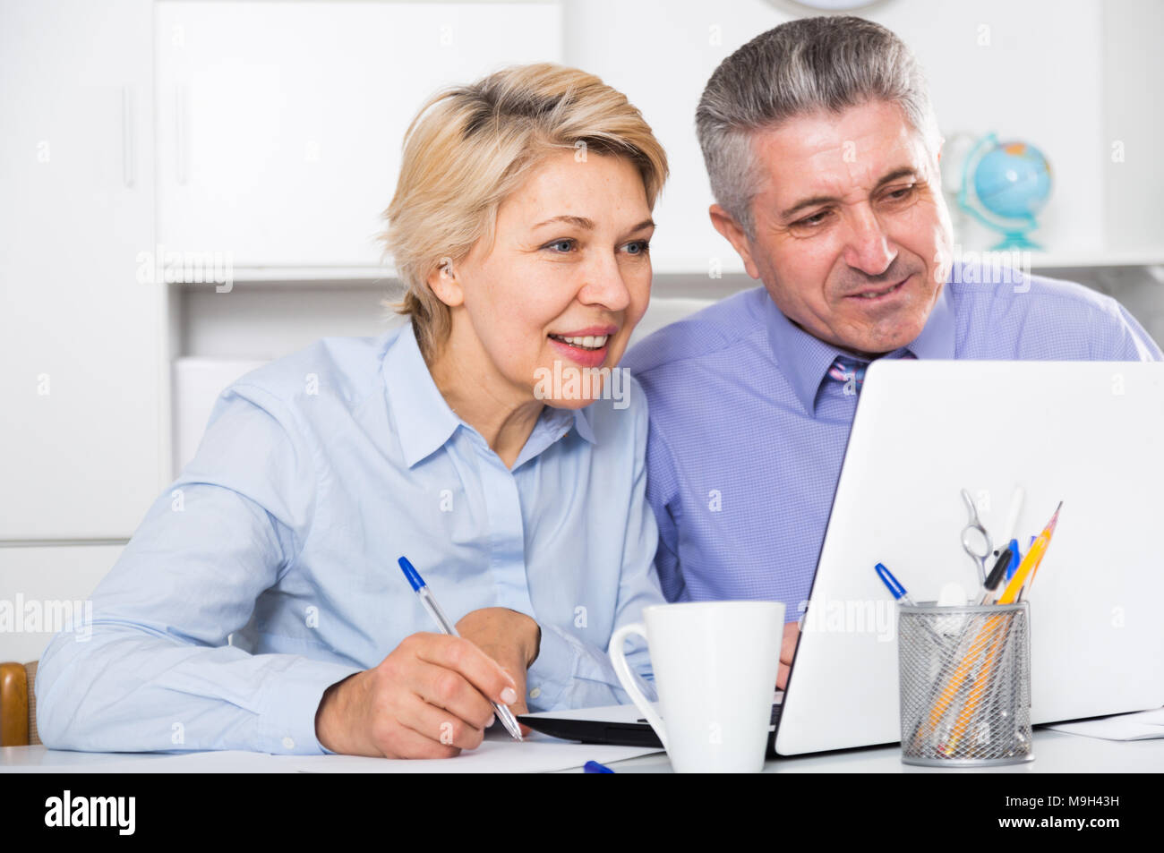 Colleagues look at screen of computer and discuss project documents ...
