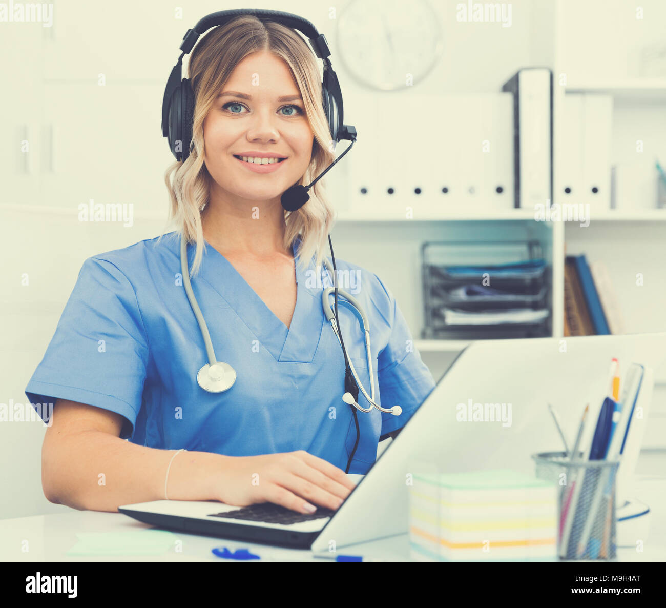 Friendly girl in headphones with microphone in medical call center ...