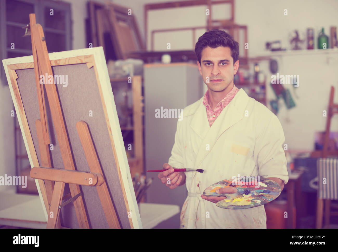 Happy art painter holding artist palette and painting on canvas Stock ...