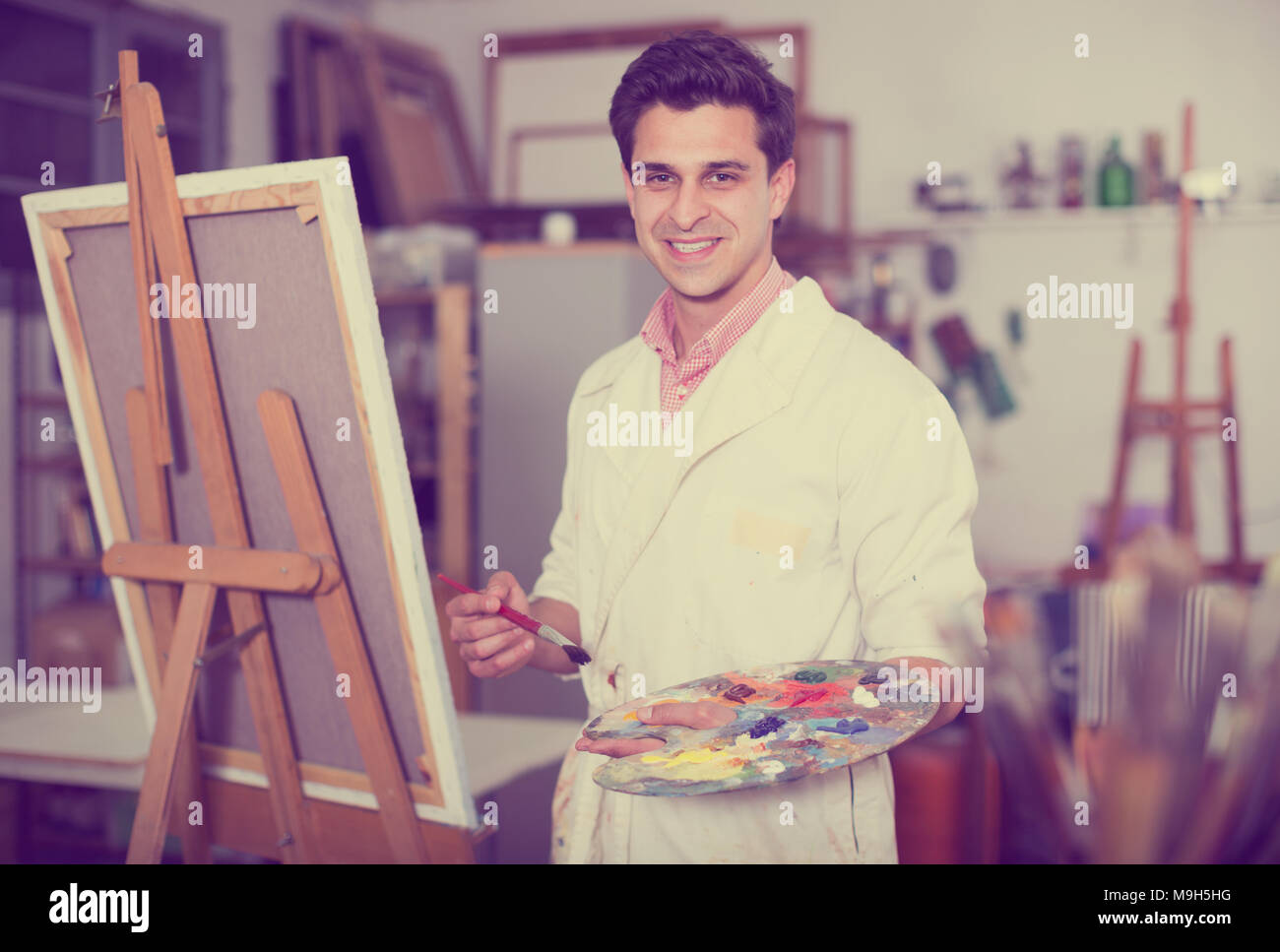 Happy art painter holding artist palette and painting on canvas Stock ...