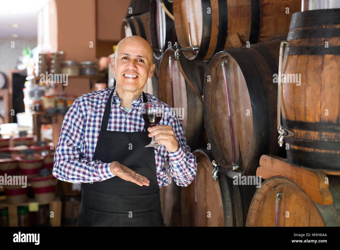 Positive male wine maker taking wine from wood in winery Stock Photo ...