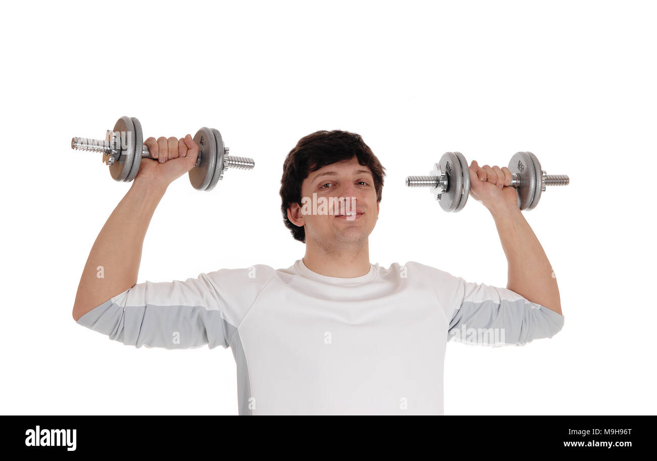 A closeup image of a young man lifting two dumbbells, looking into the ...