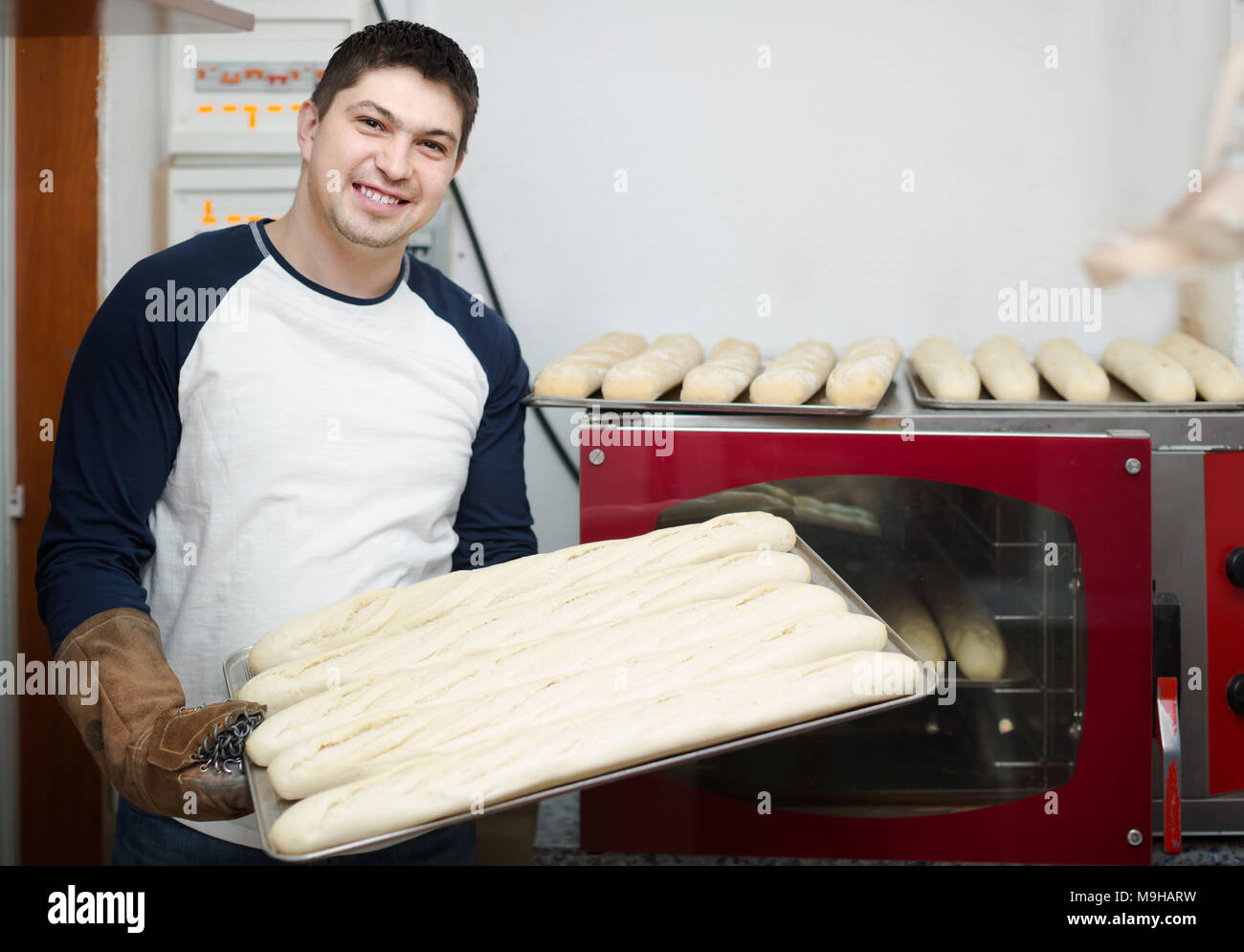 Ordinary male baker with bread near oven at supermarket Stock Photo - Alamy