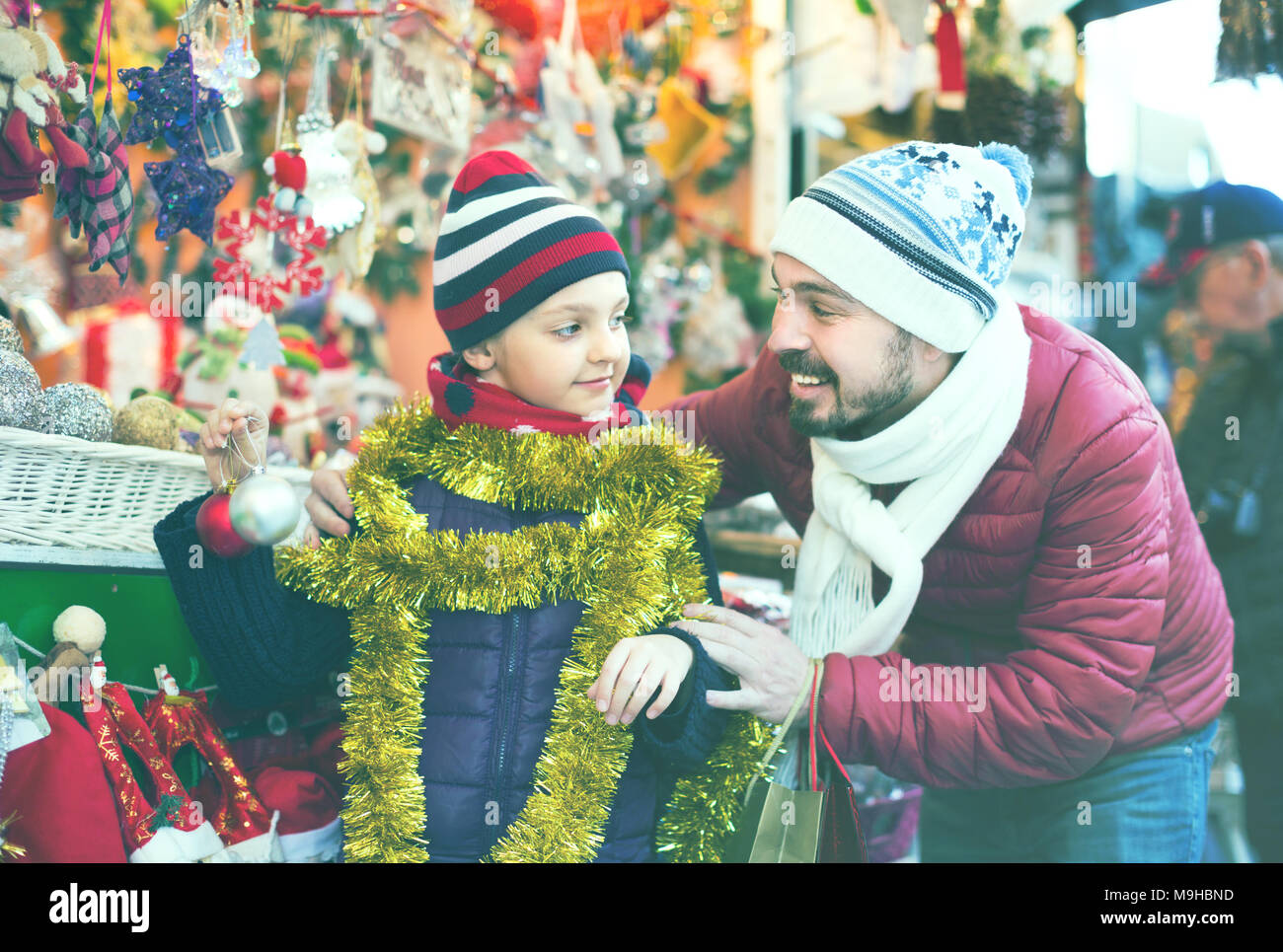 Positive dad with little daughter are smiling and choosing decorations ...