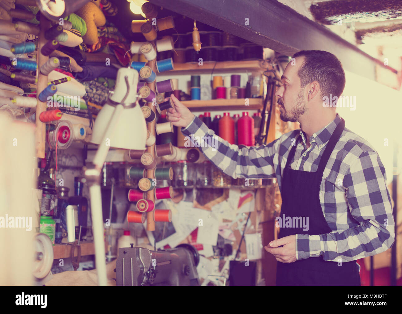 Male worker choosing thread for sewing in leather workshop Stock Photo ...