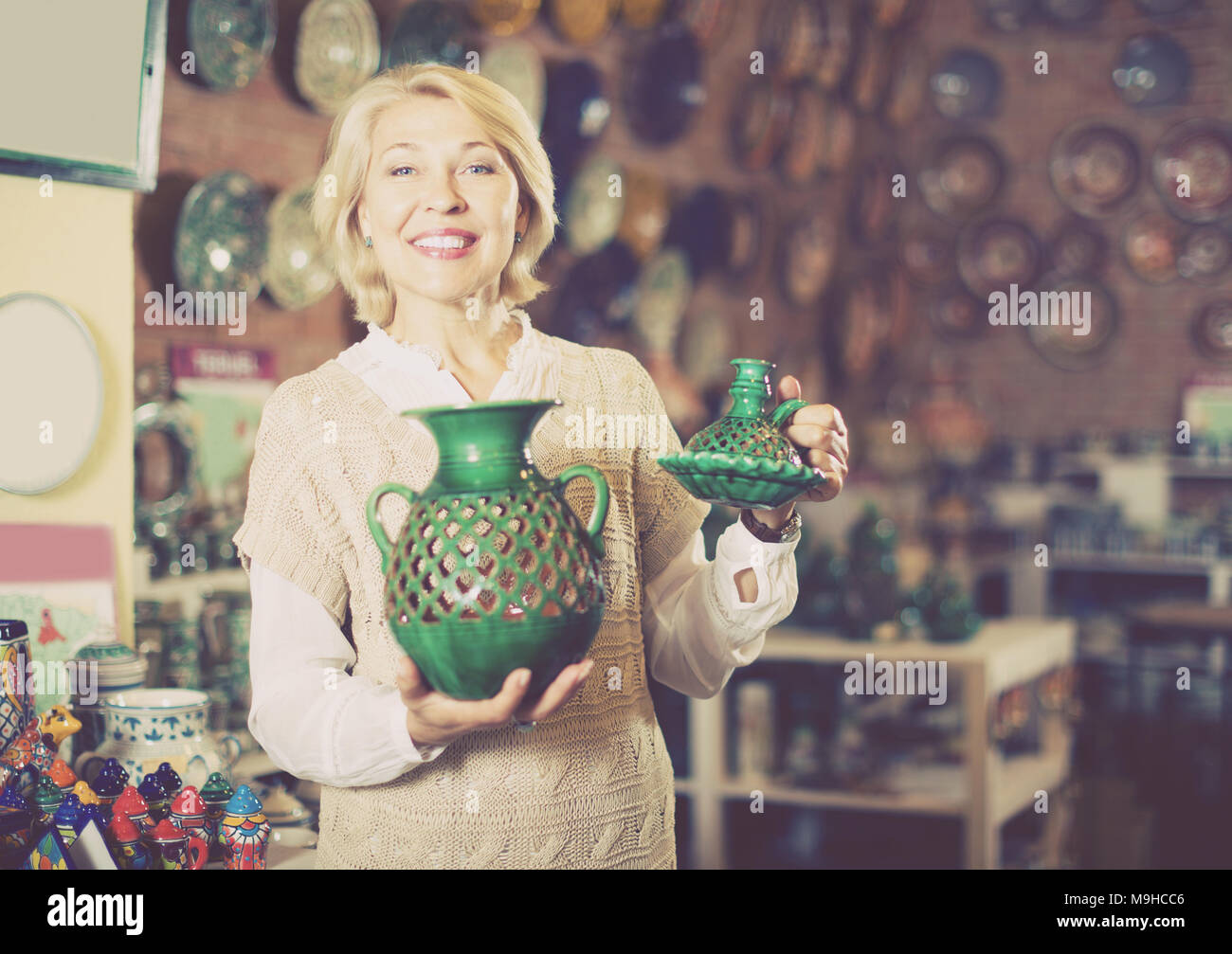 Happy mature woman posing with homemade ceramic cookware at workshop ...