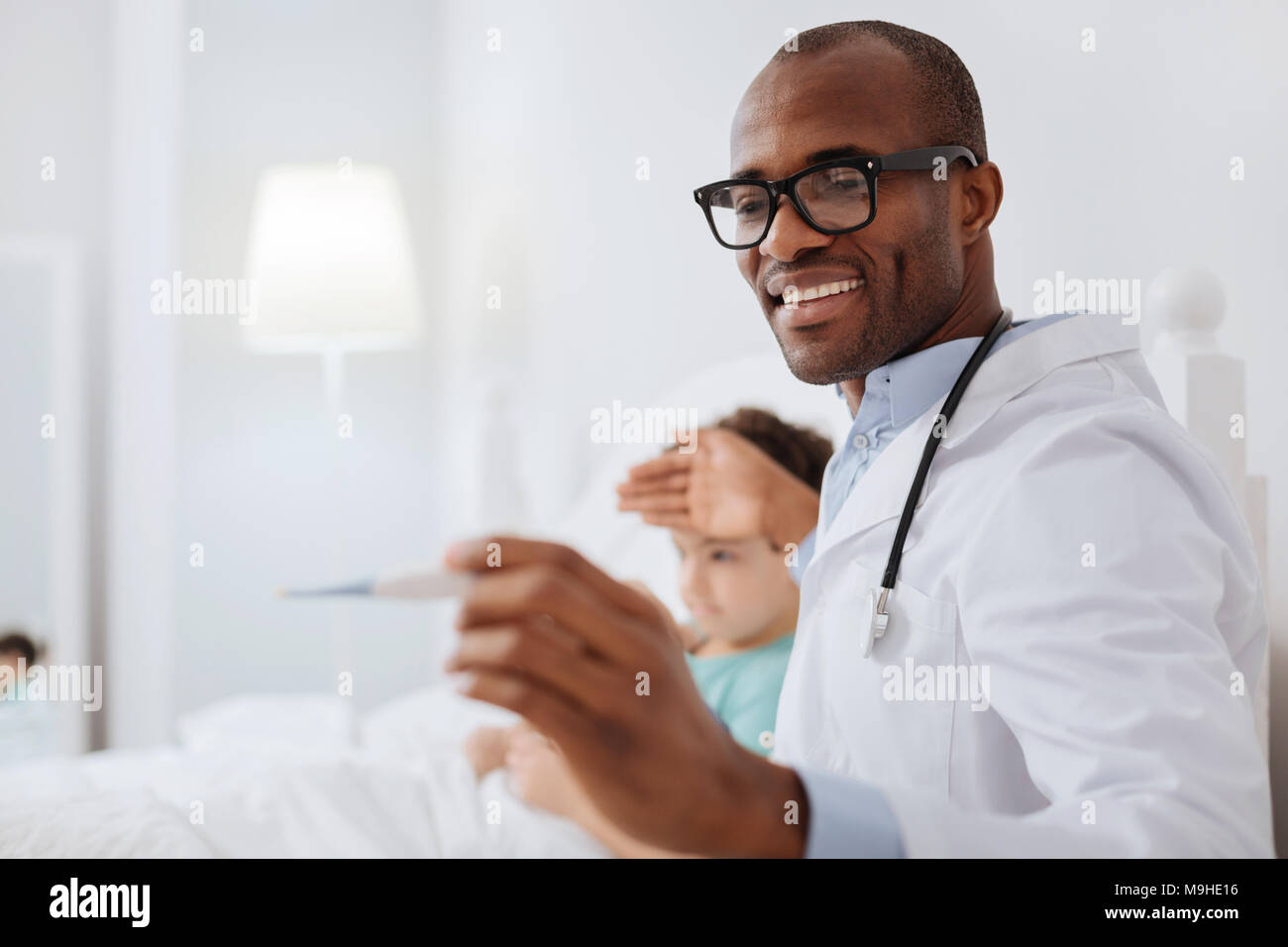 Merry male doctor verifying boys temperature Stock Photo - Alamy