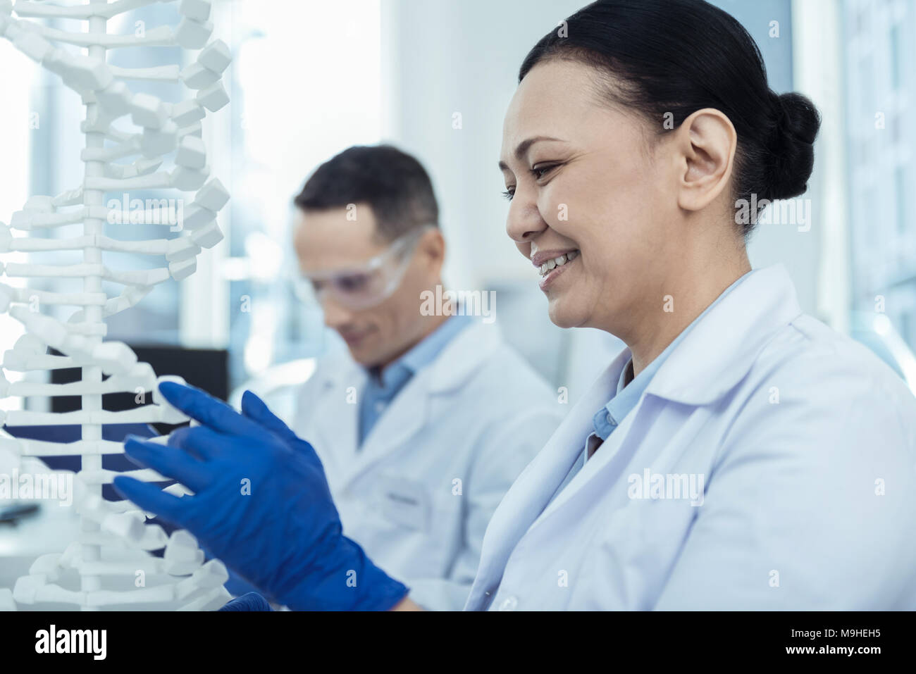 Positive asian woman studying dna model in a lab Stock Photo - Alamy