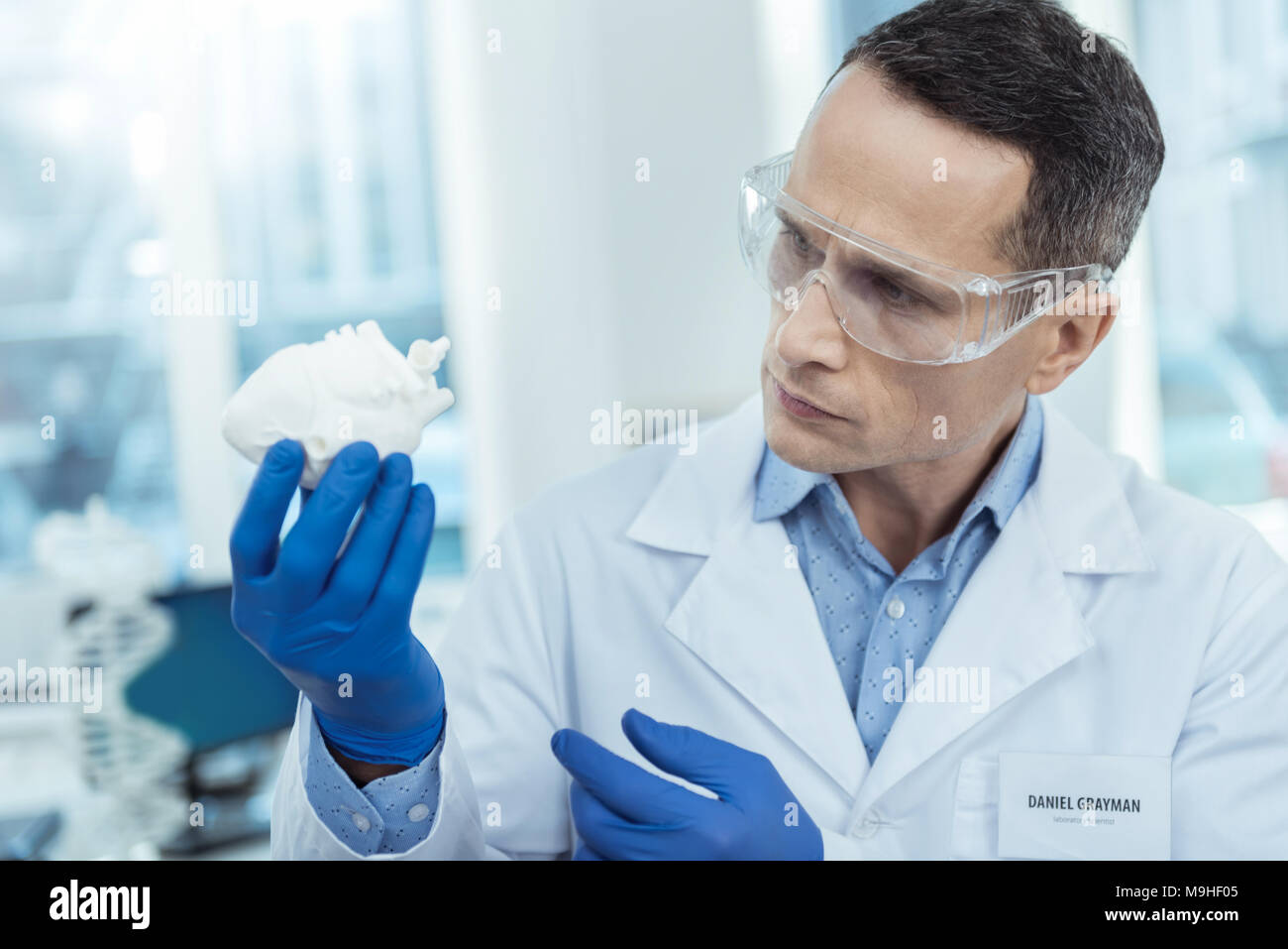 Professional researcher holding a model of heart while studying ...