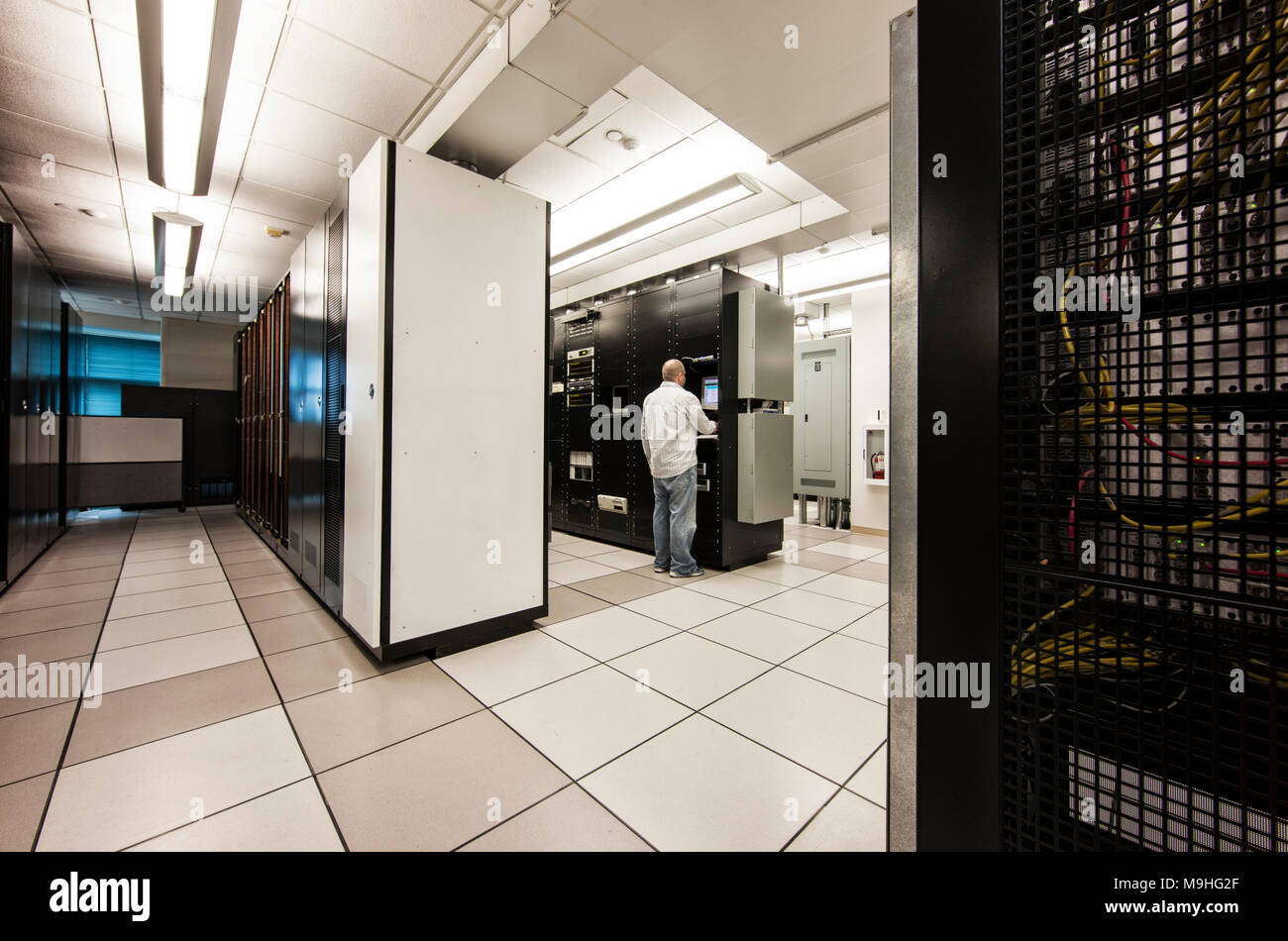 Computer server room racks with technician in background Stock Photo ...