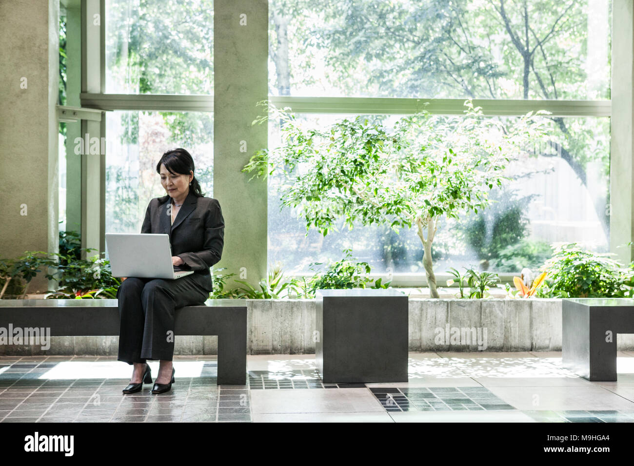 Asian businesswoman working in a large open lobby area Stock Photo - Alamy