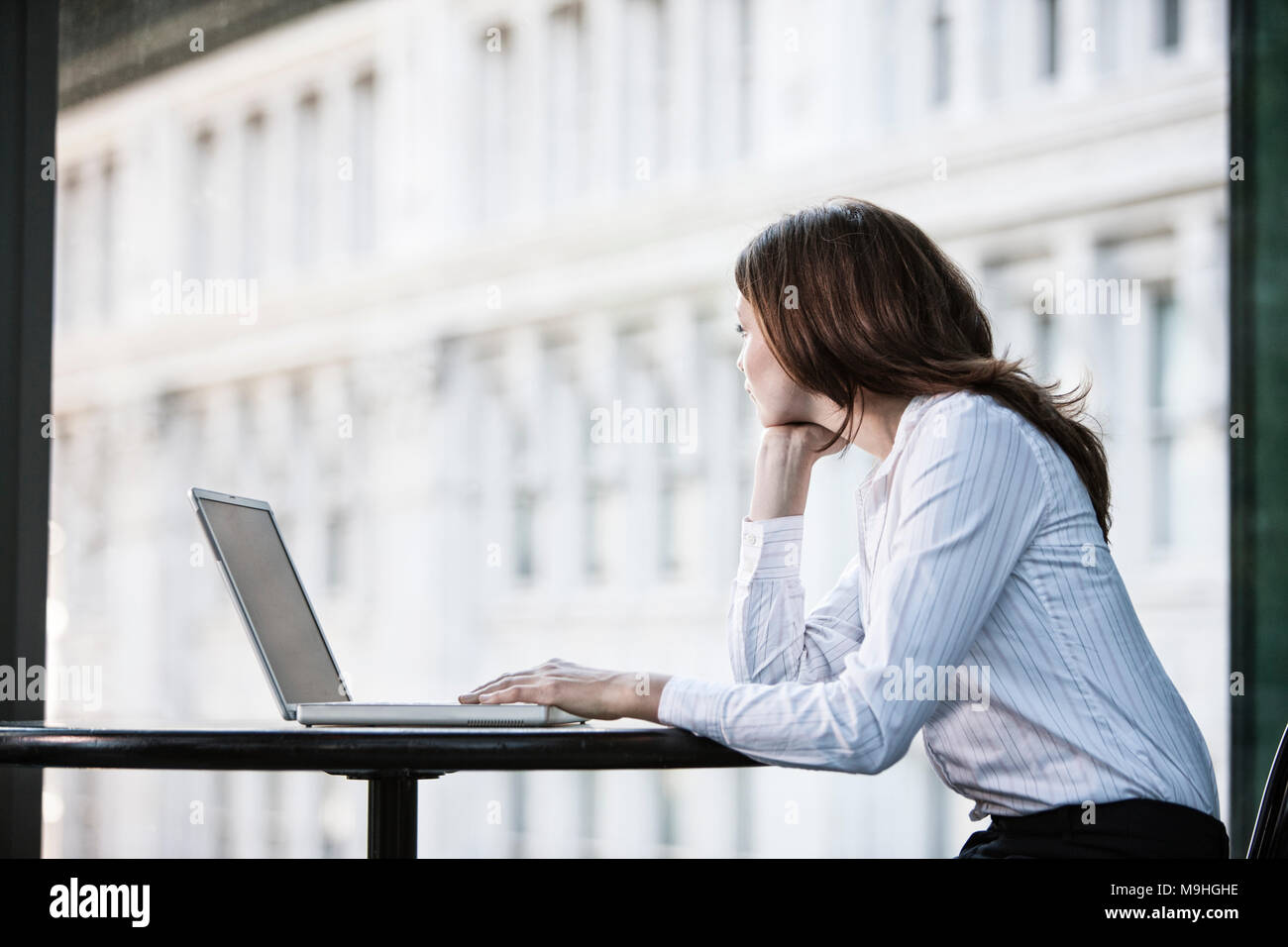 Caucasian business woman working on a laptop computer at a table in a ...