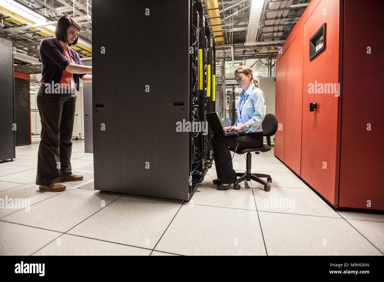 Technicians examining servers in data hi-res stock photography and ...
