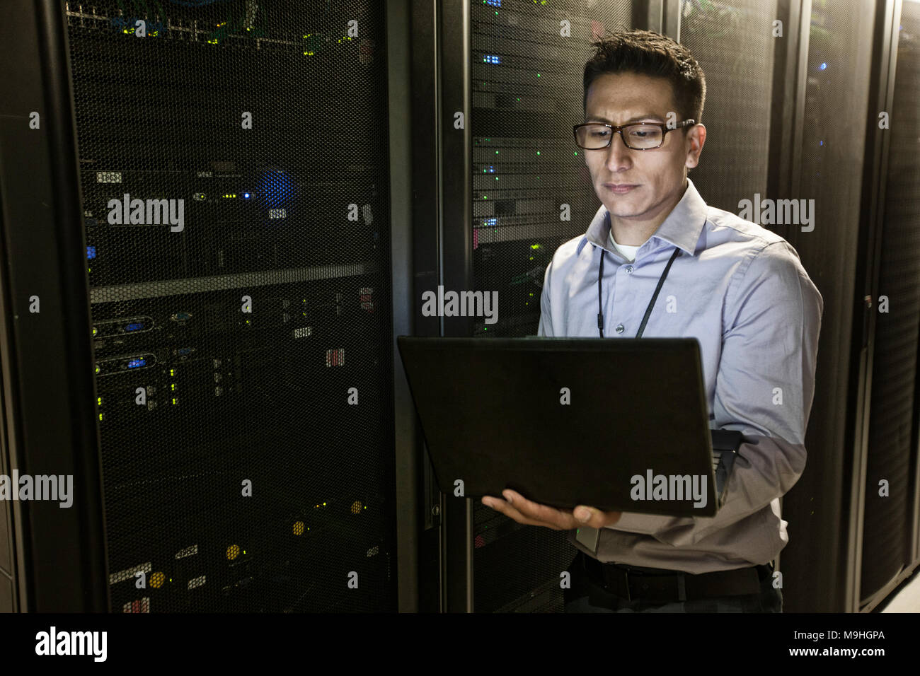 Hispanic man technician doing diagnostic tests on computer servers in a ...