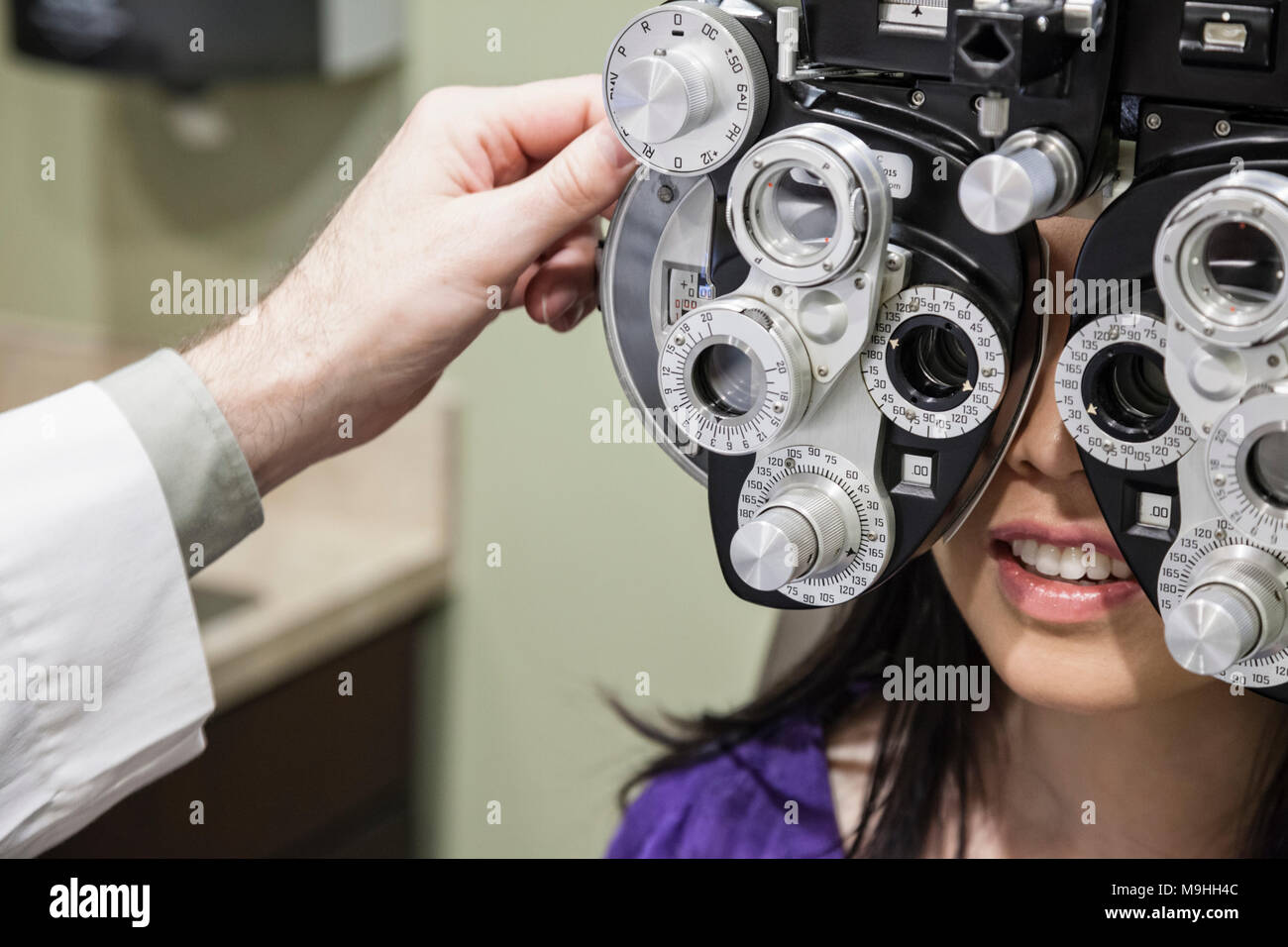 Opthamologist using a phoropter instrument to adjust an eyeglass ...