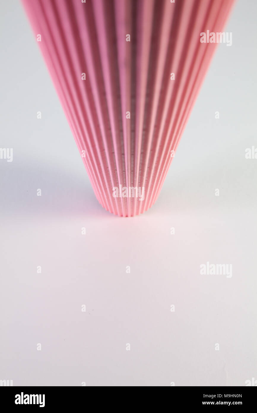 Corrugated pink paper roll on the white desk. Symmetry composition ...
