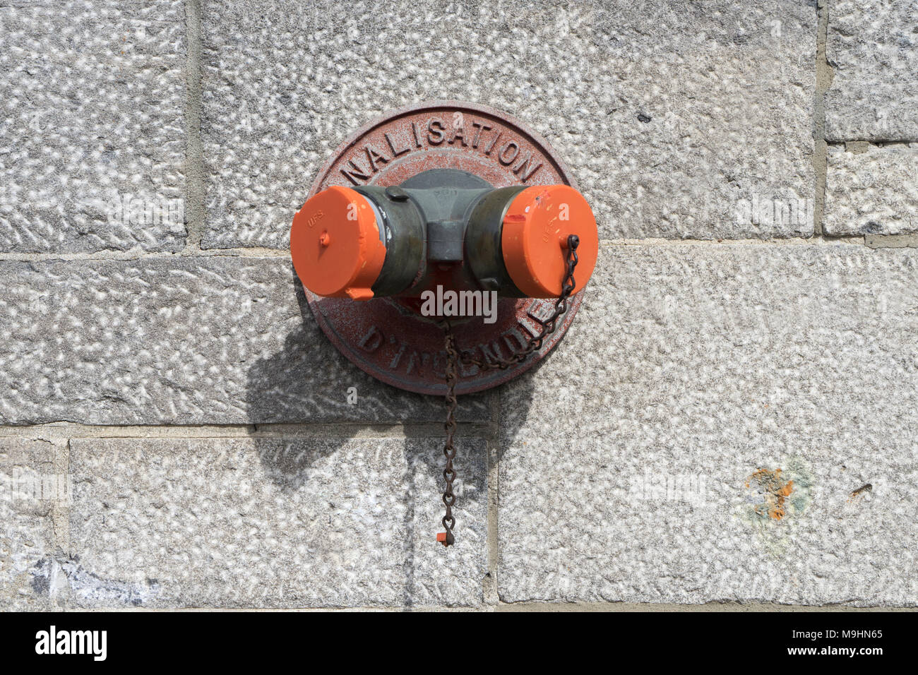 Fire hydrant mounted on the exterior stone wall of a building Stock ...