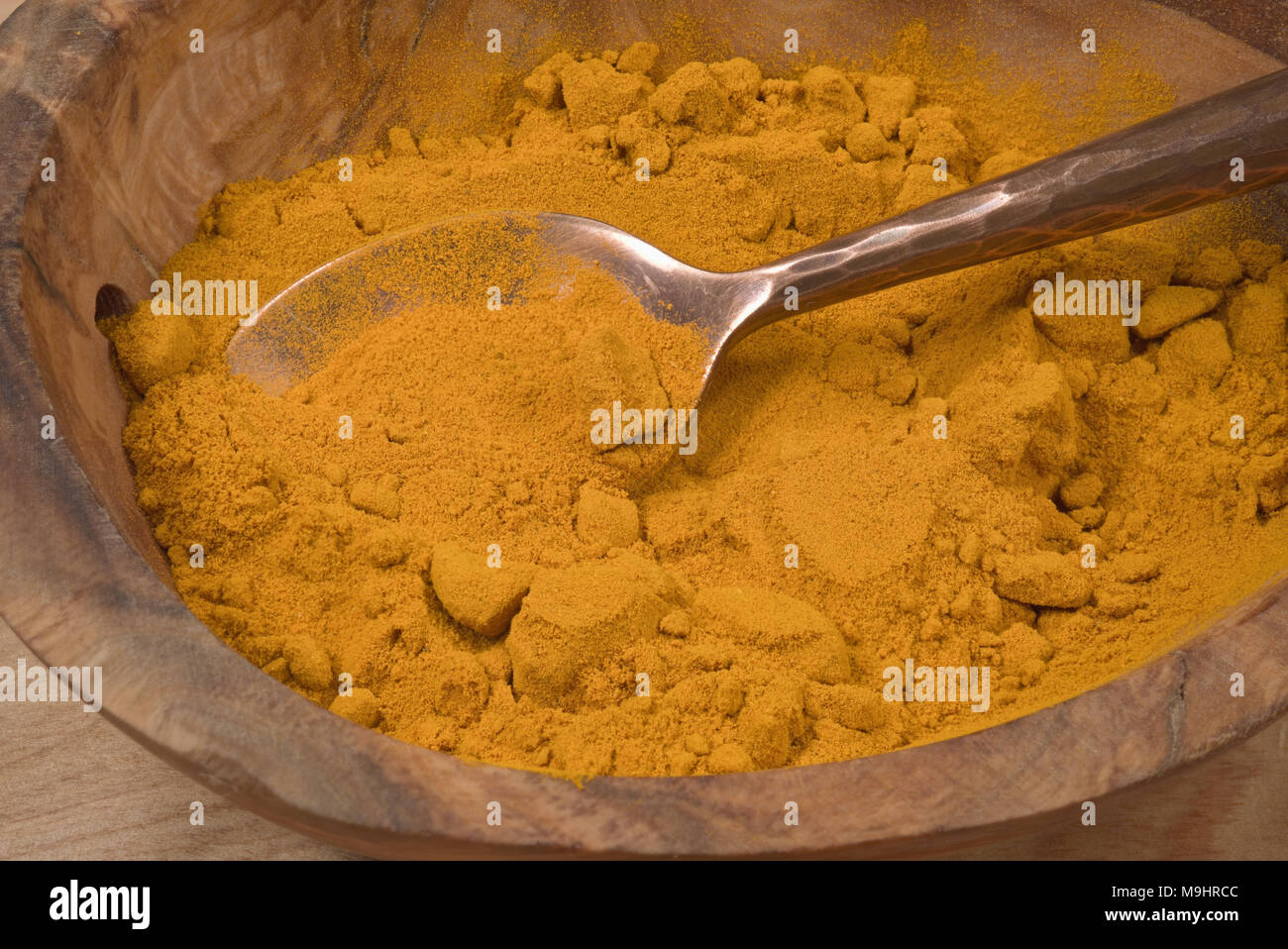 Turmeric root powder in wood bowl with copper spoon Stock Photo - Alamy