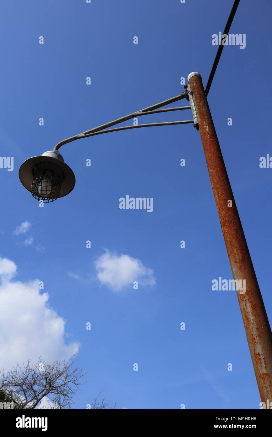 Old street lamp, paint on peeling off, rust, blue sky, small white ...