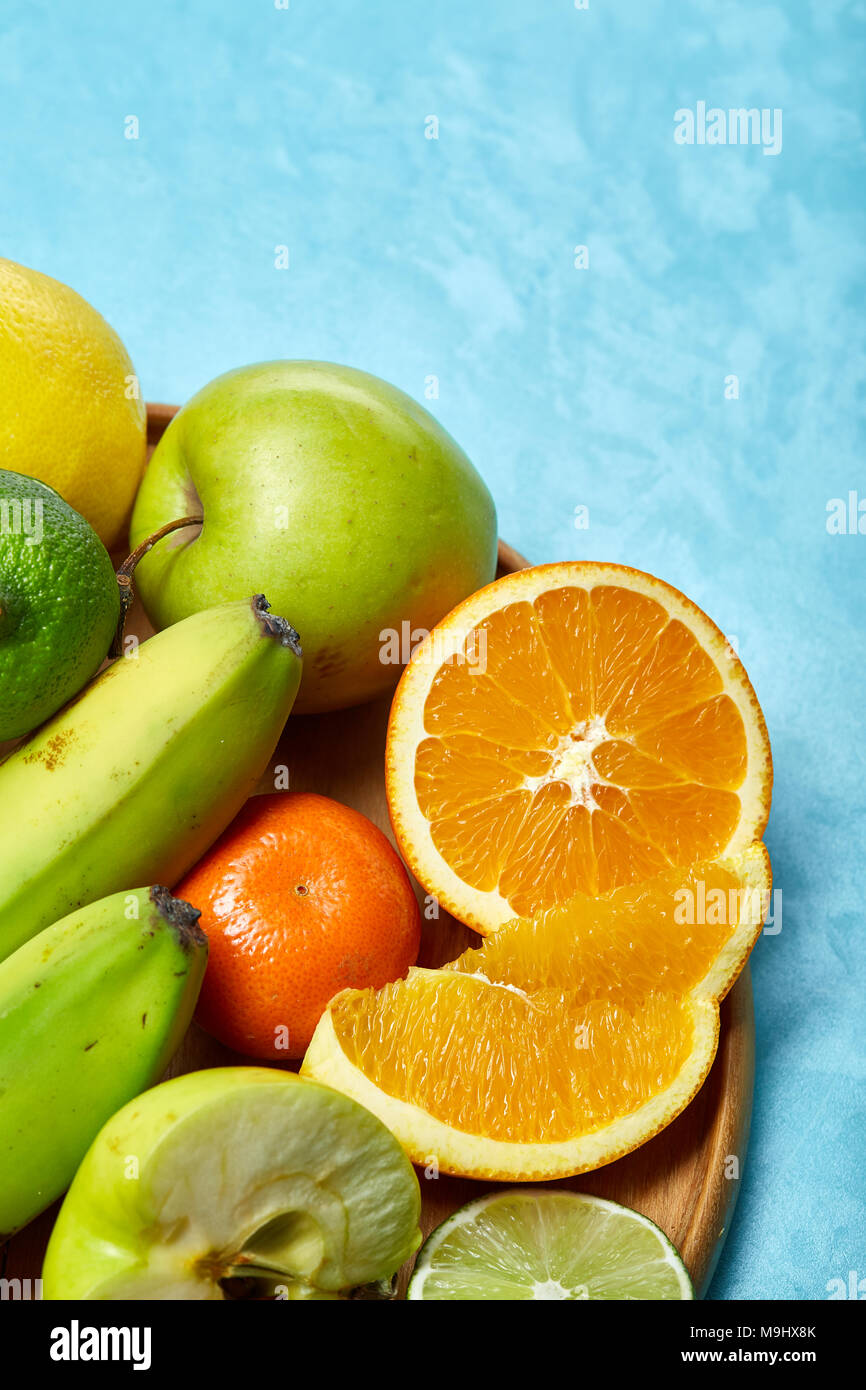 Ripe fresh fruits in a wooden plate on a blue background, selective ...