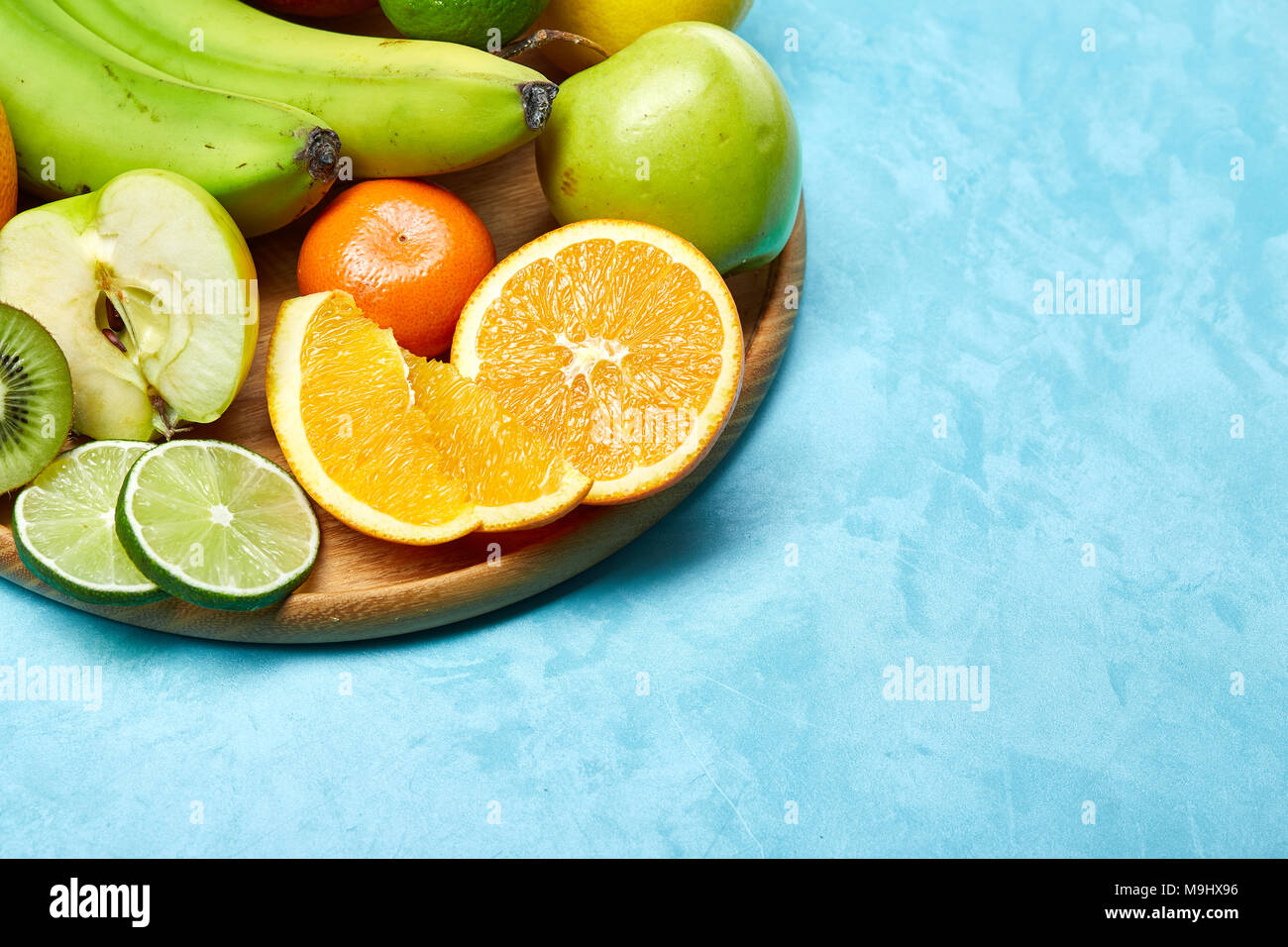 Ripe fresh fruits in a wooden plate on a blue background, selective ...
