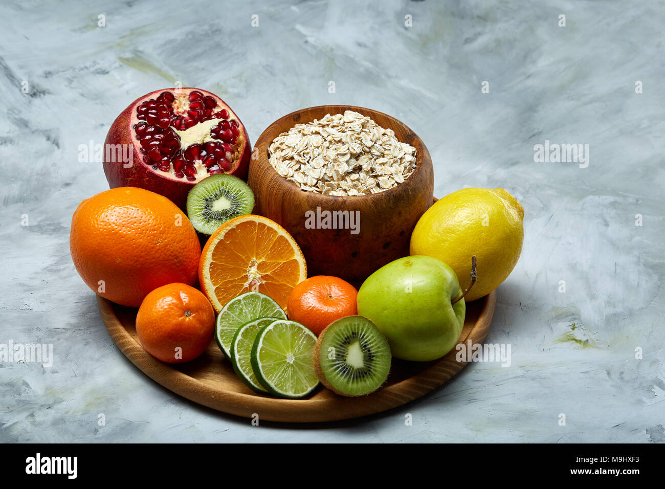 Ripe fresh fruits in a wooden plate on a light background, selective ...