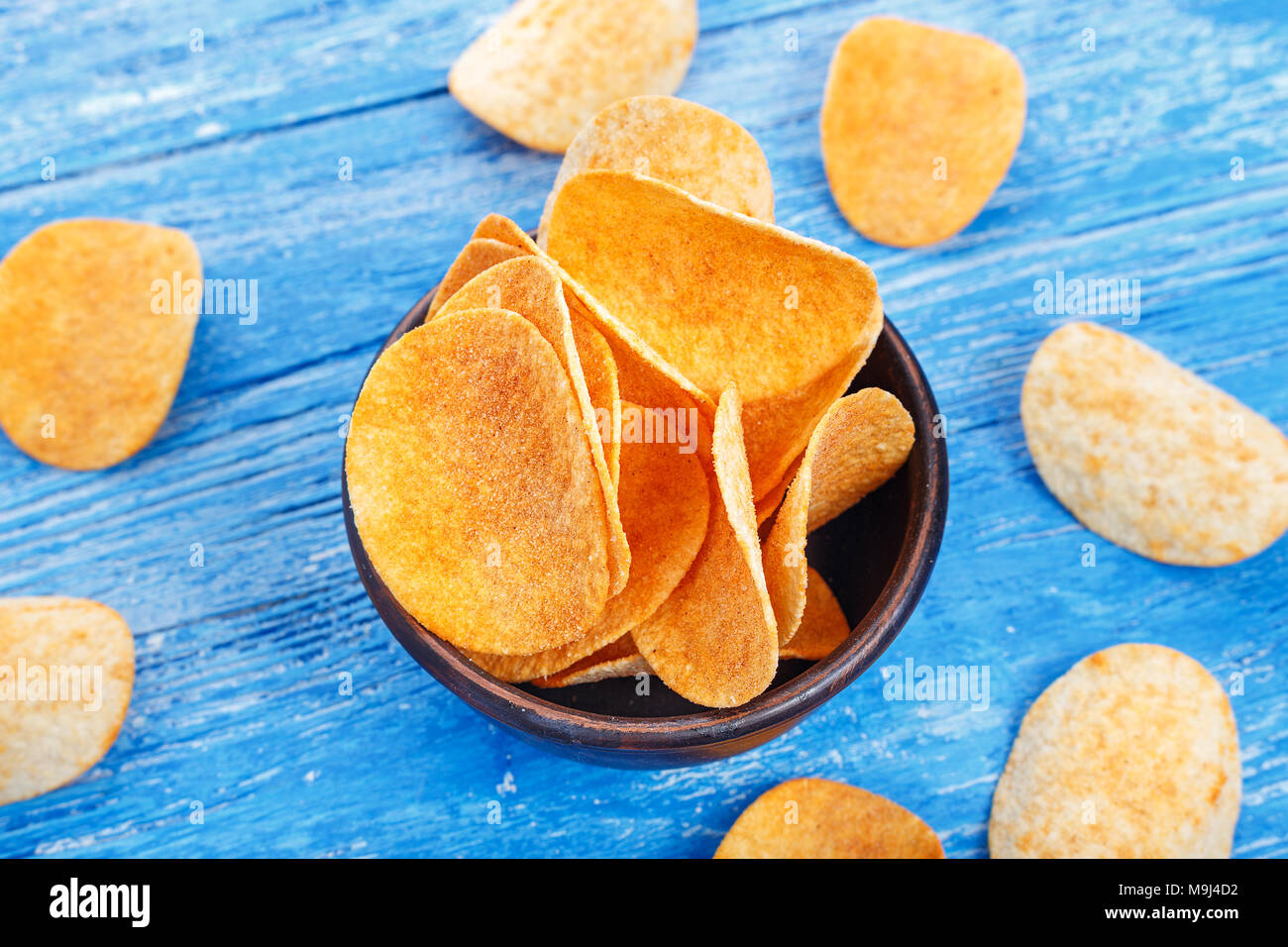 Crispy potato chips in a earthenware dish on blue kitchen table Stock ...