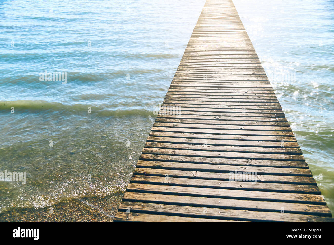 wooden pier path over water with waves on a sunny summer day Stock ...