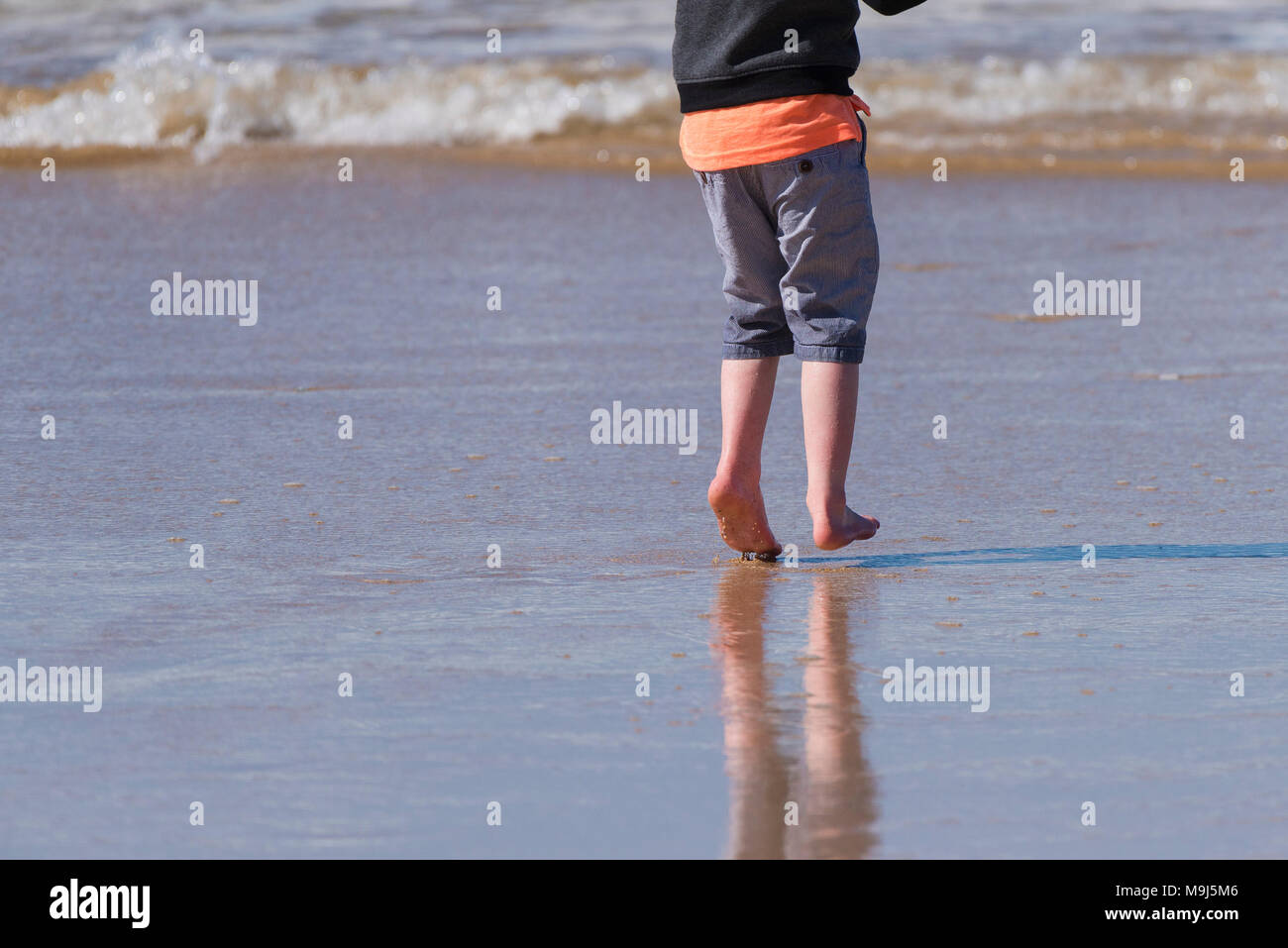 A young child paddling in the sea at Fistral Beach in Newquay Cornwall ...