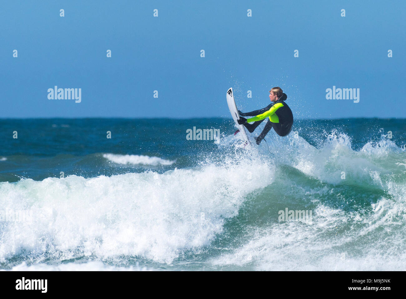 A surfer performing a spectacular aerial trick from the top of a wave ...