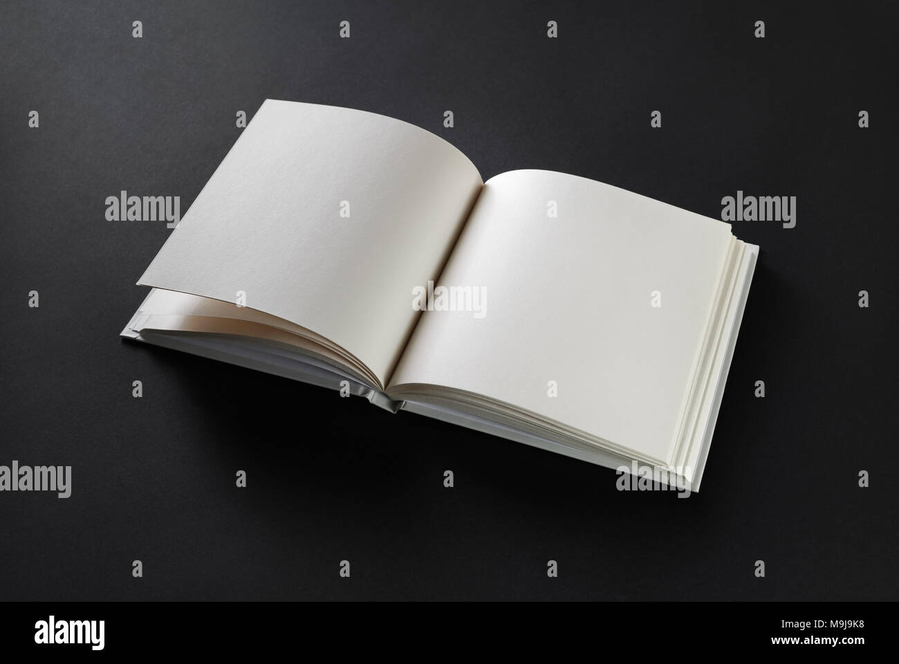 Open blank square book on black paper background Stock Photo - Alamy