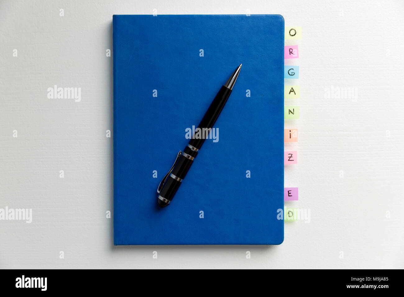 Blue note book with pen and colorful post it separators between sheets ...